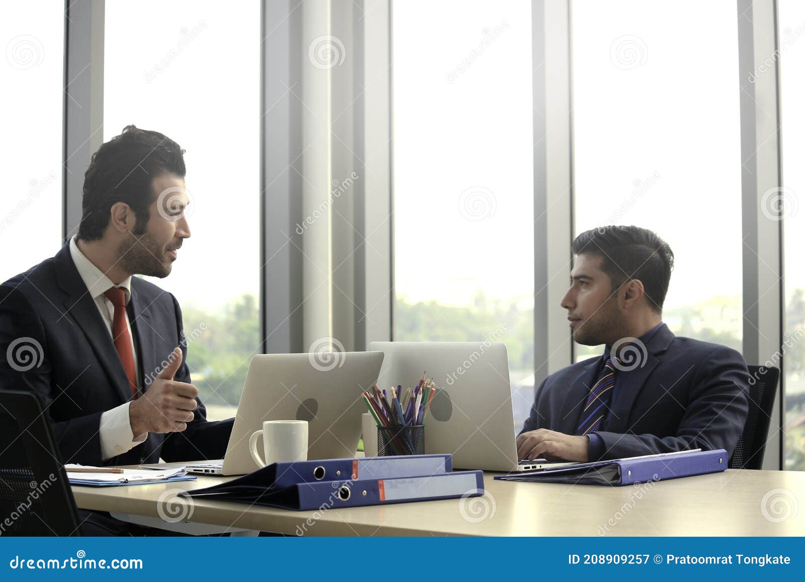 Two Young Businessmen Using Laptop Computer Seriously Discussing about ...