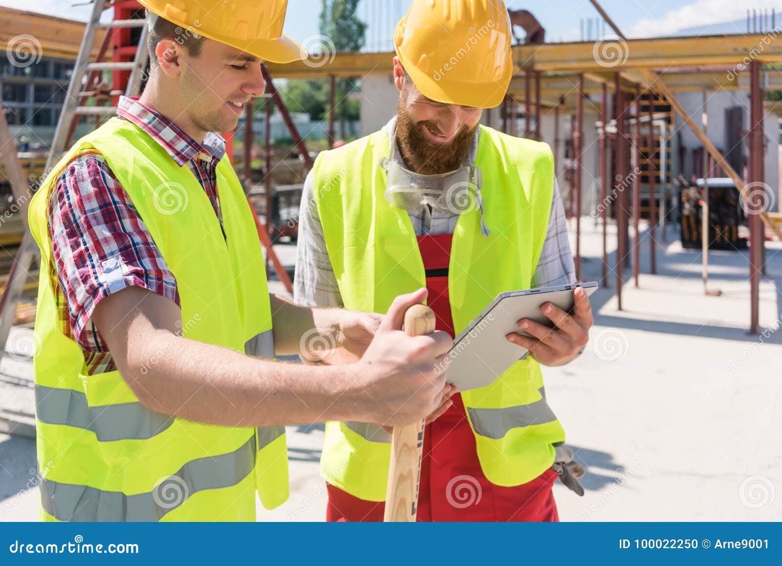 Two Young Construction Workers Smiling while Using a Tablet Duri Stock ...