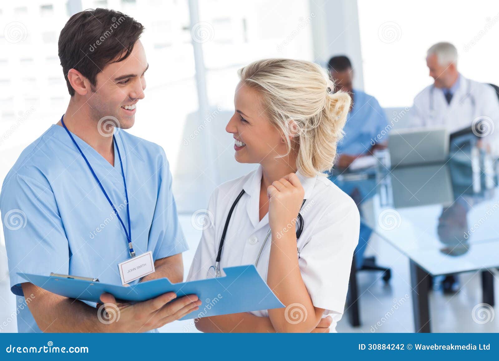 Two Young Doctors Talking about a Blue File Stock Photo - Image of ...
