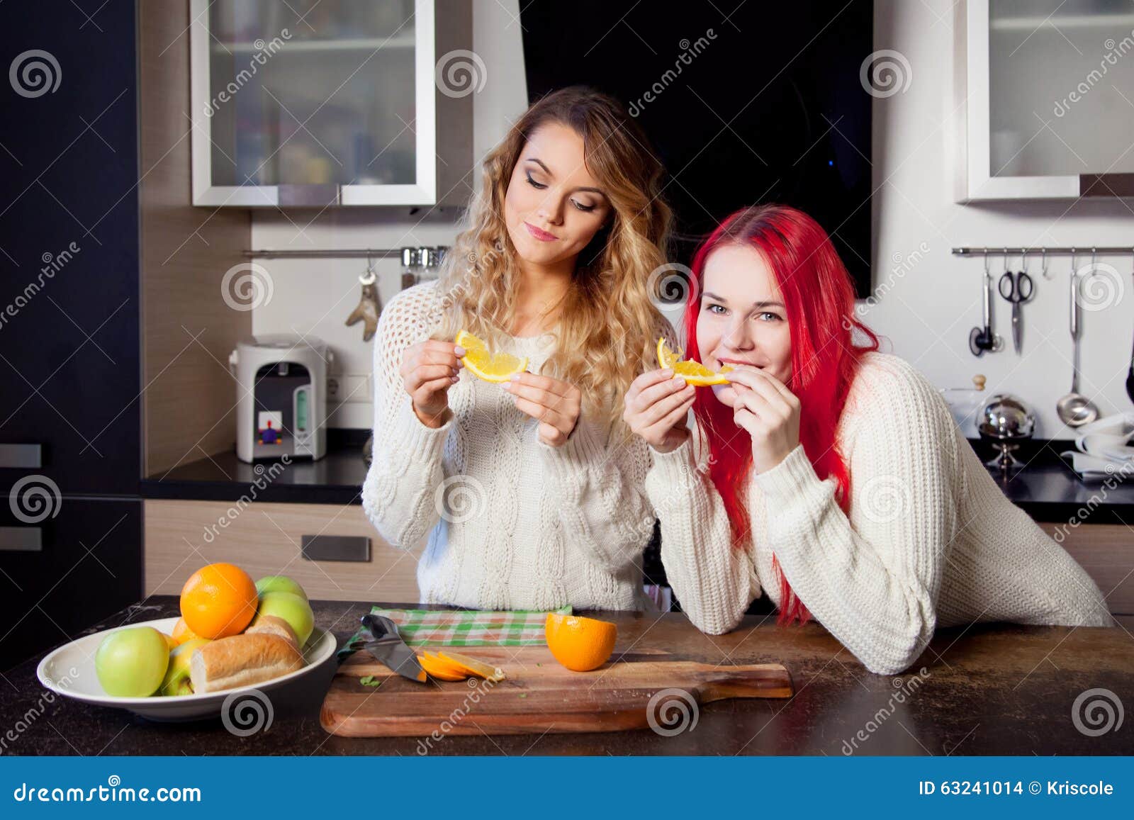 Two Young Girls in the Kitchen Talking and Eating Stock Photo - Image ...