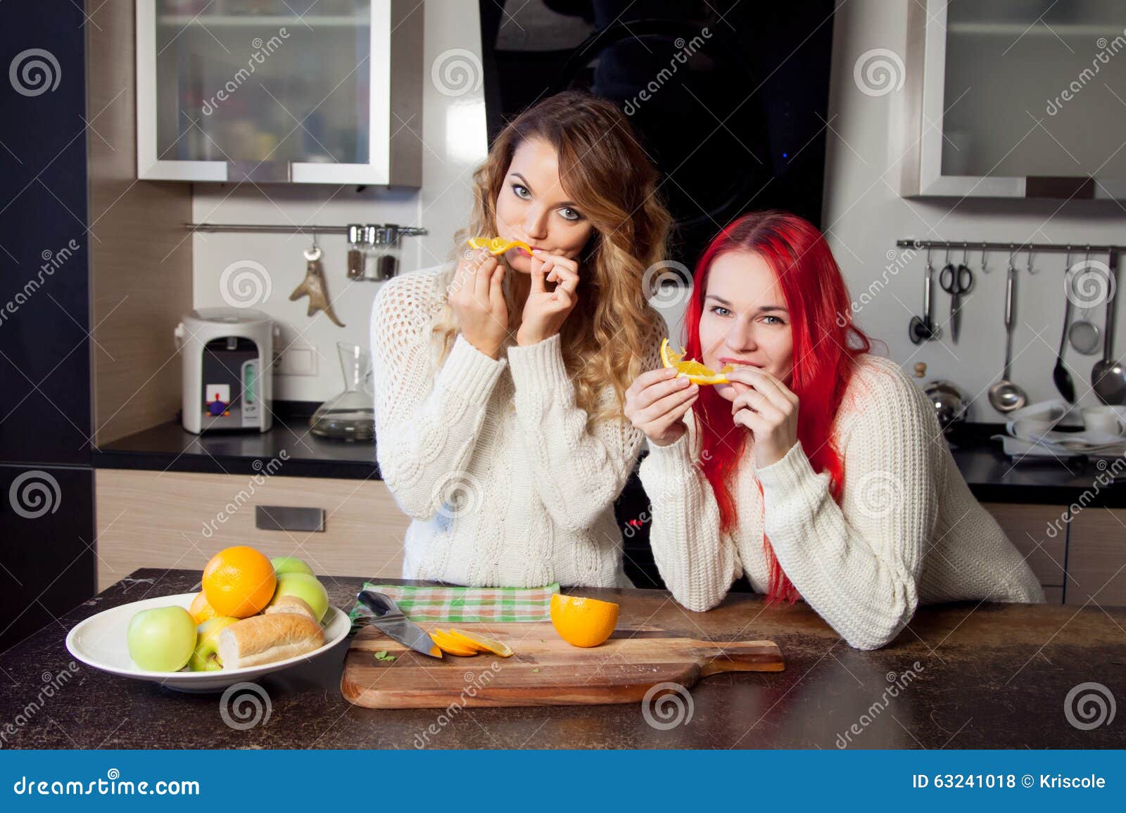 Two Young Girls in the Kitchen Talking and Eating Stock Photo - Image ...