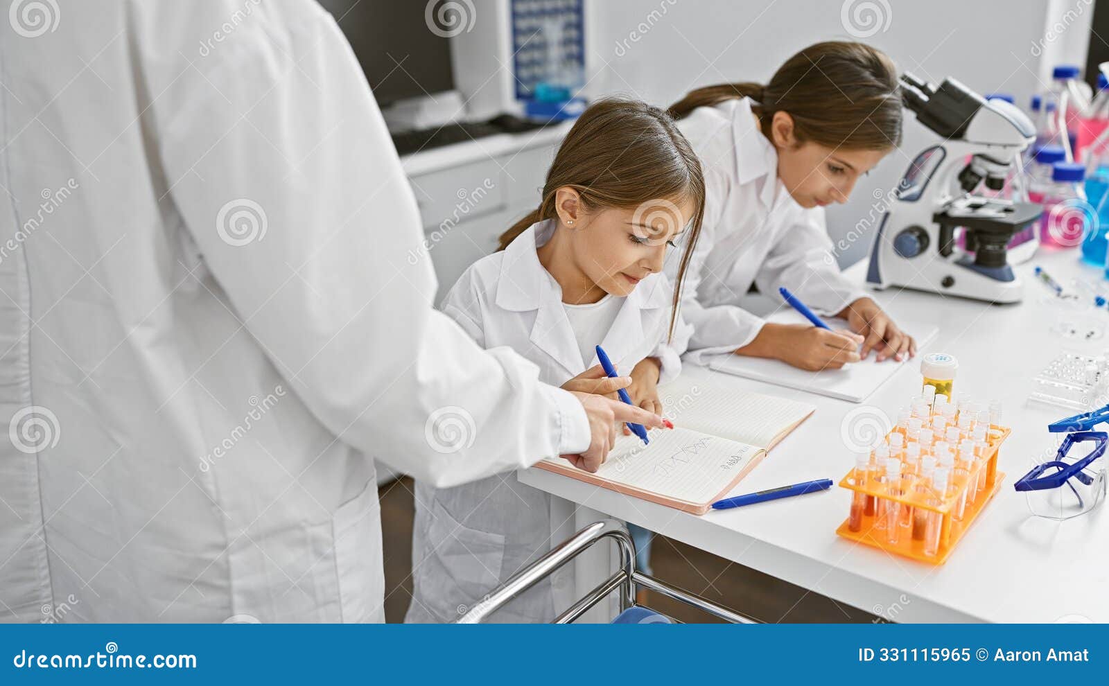 Two Young Girls in Lab Coats Taking Notes in a Science Laboratory with ...