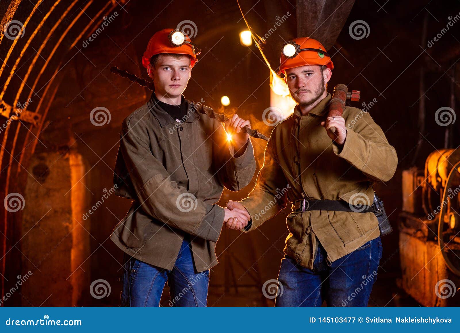 Two Young Guys in Working Uniform and Protective Helmets, Shaking Hands ...