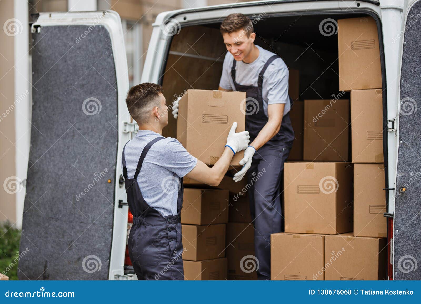 Two Young Handsome Movers Wearing Uniforms are Unloading the Van Full ...