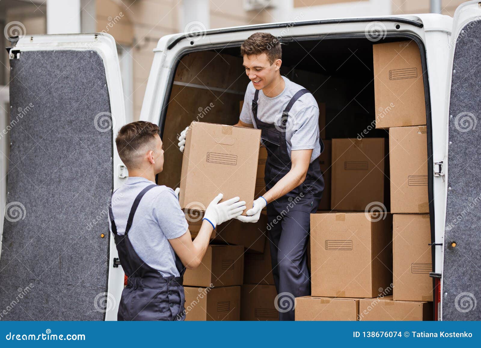 Two Young Handsome Movers Wearing Uniforms are Unloading the Van Full ...