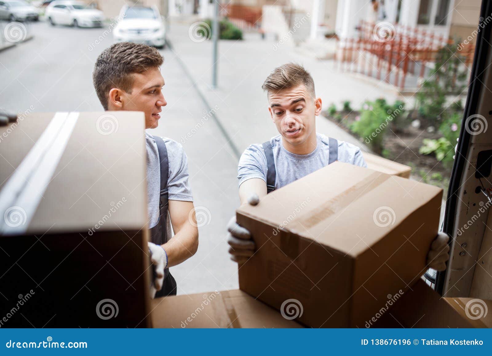 Two Young Handsome Smiling Movers Wearing Uniforms are Unloading the ...