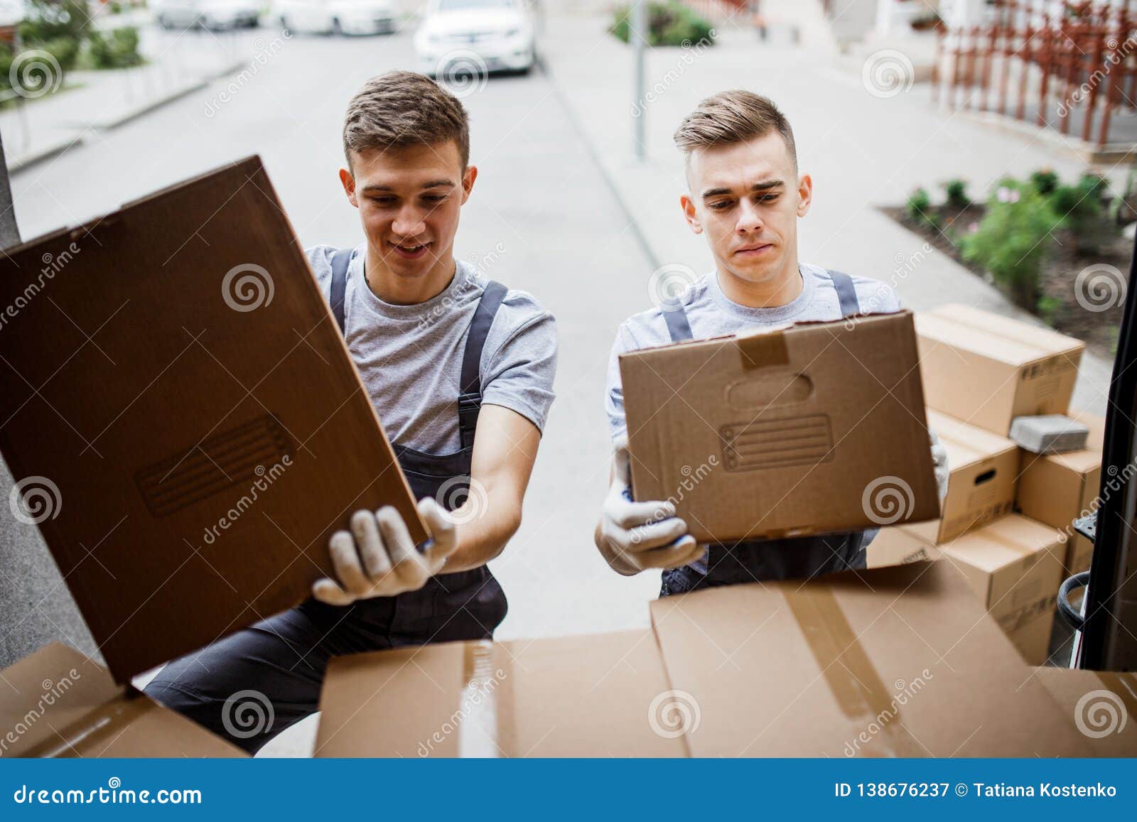 Two Young Handsome Smiling Movers Wearing Uniforms are Unloading the ...