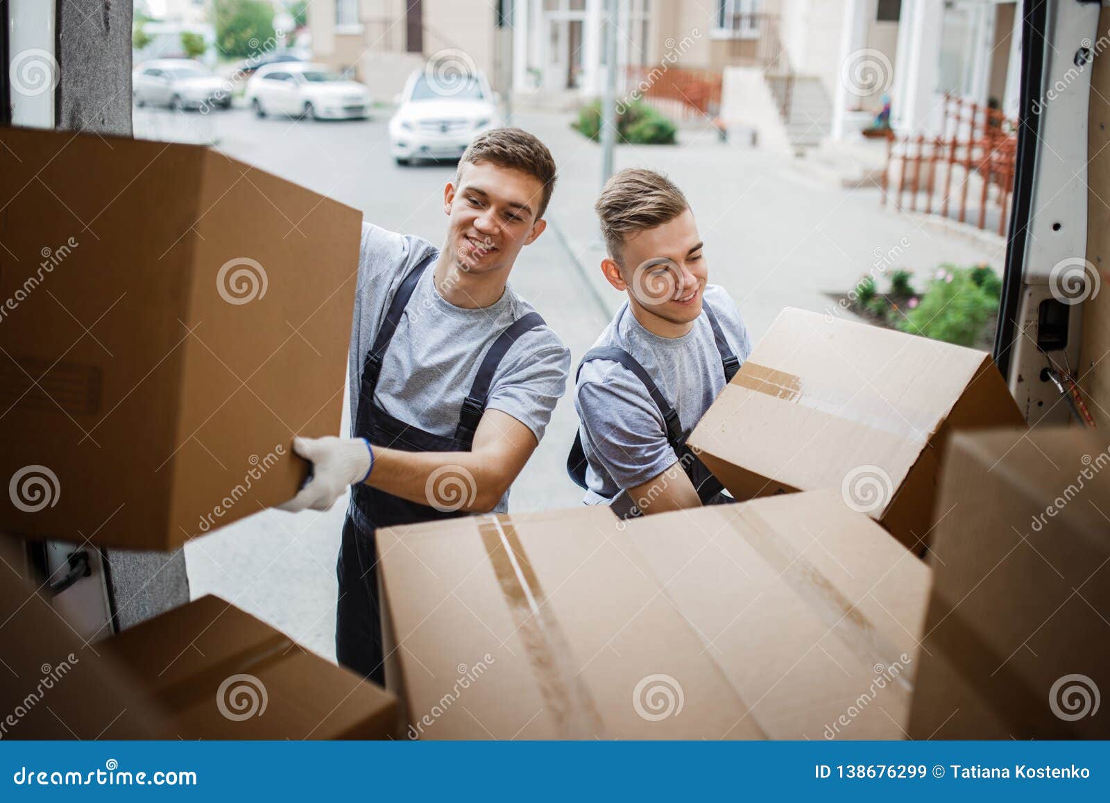 Two Young Handsome Smiling Movers Wearing Uniforms are Unloading the ...