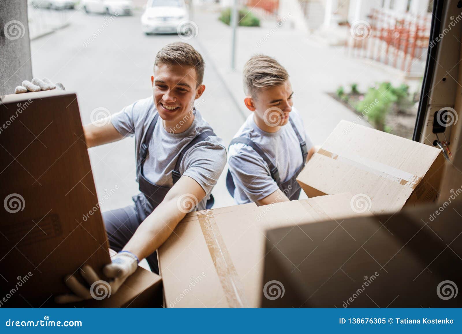 Two Young Handsome Smiling Movers Wearing Uniforms are Unloading the ...
