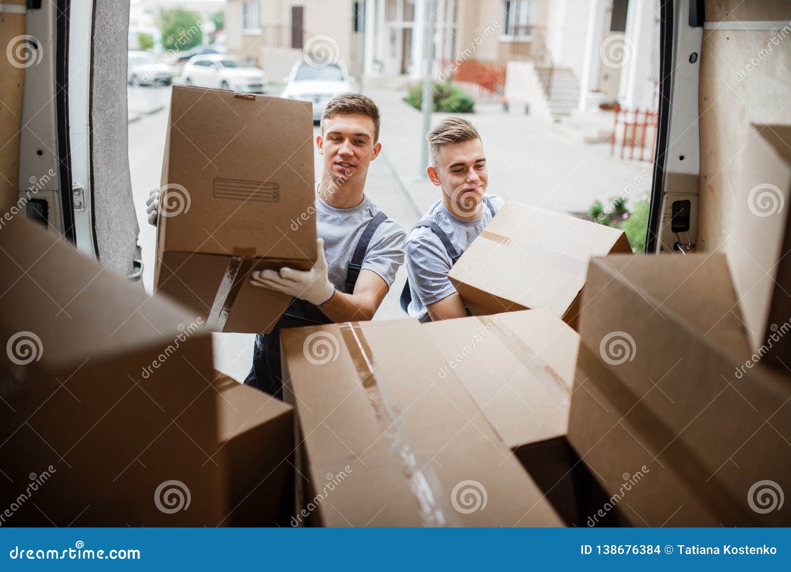 Two Young Handsome Smiling Movers Wearing Uniforms are Unloading the ...