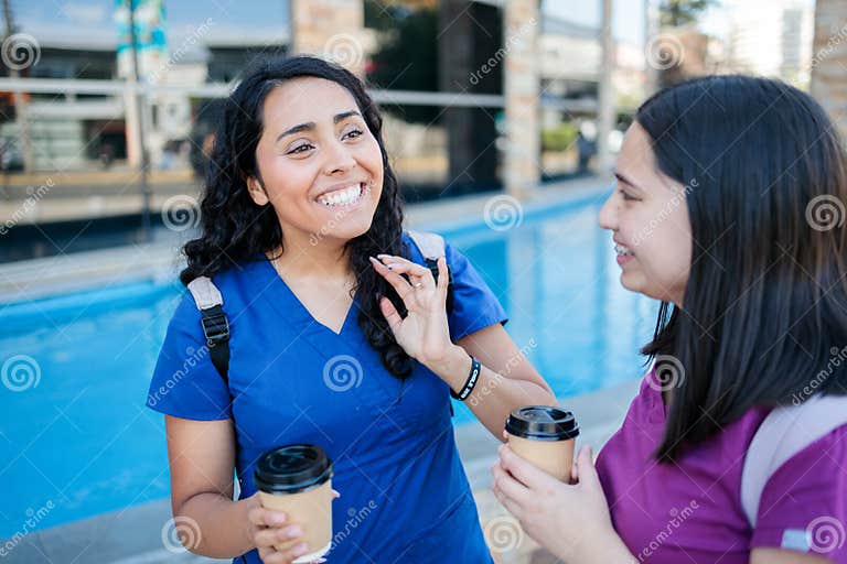 Two Young Hardworking Latin Nurses Talking With Cup Of Coffee After
