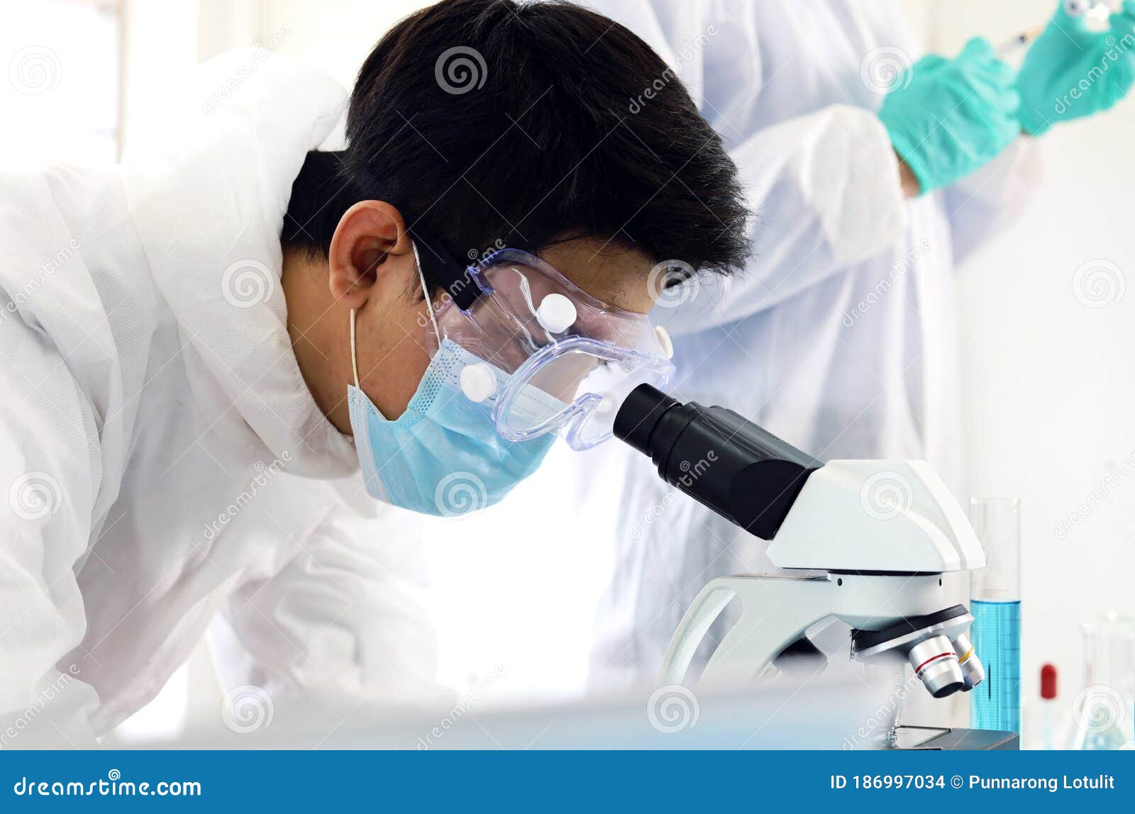 Two Young Men Scientist Using a Microscope for Looking Solution in ...