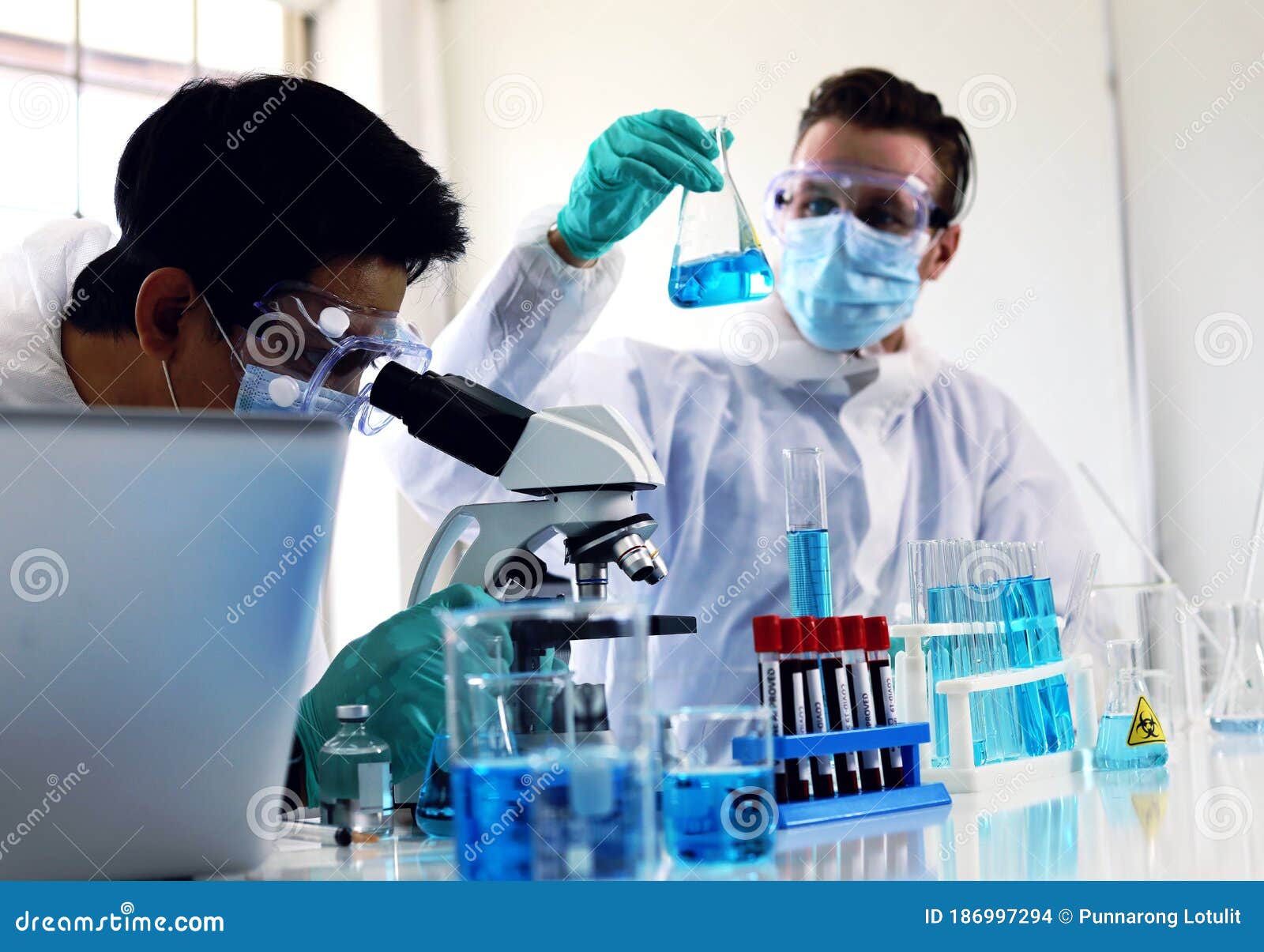 Two Young Men Scientist Using a Microscope for Looking Solution in ...