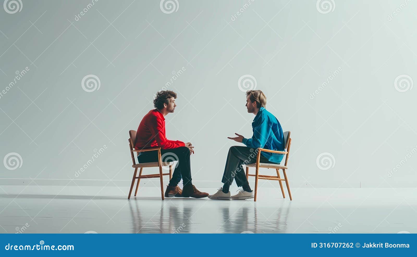 Two Young Men Sitting on Chairs and Talking on Grey Background with ...