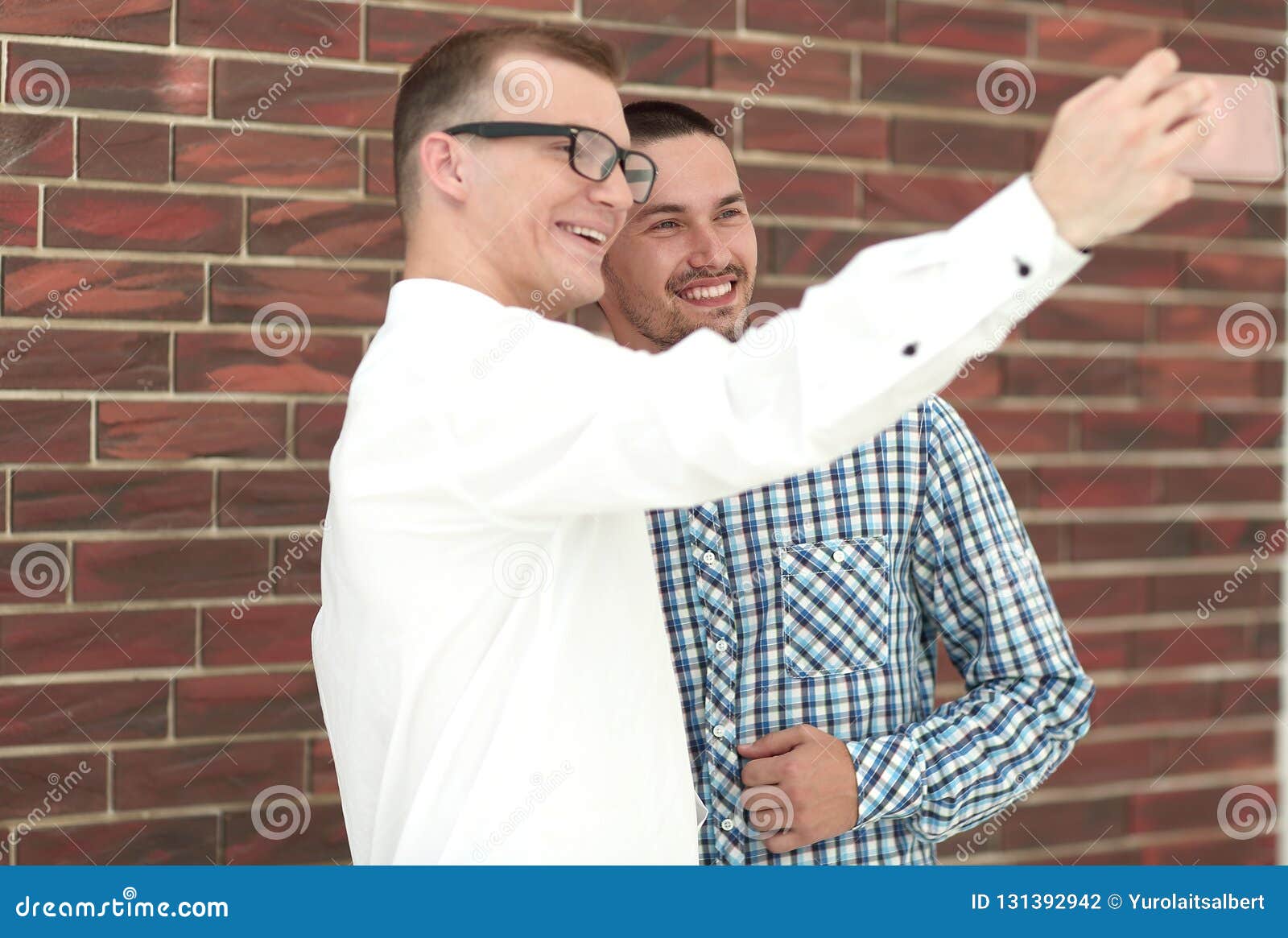Two Young Men Taking Selfies Standing Near a Brick Wall Stock Photo ...