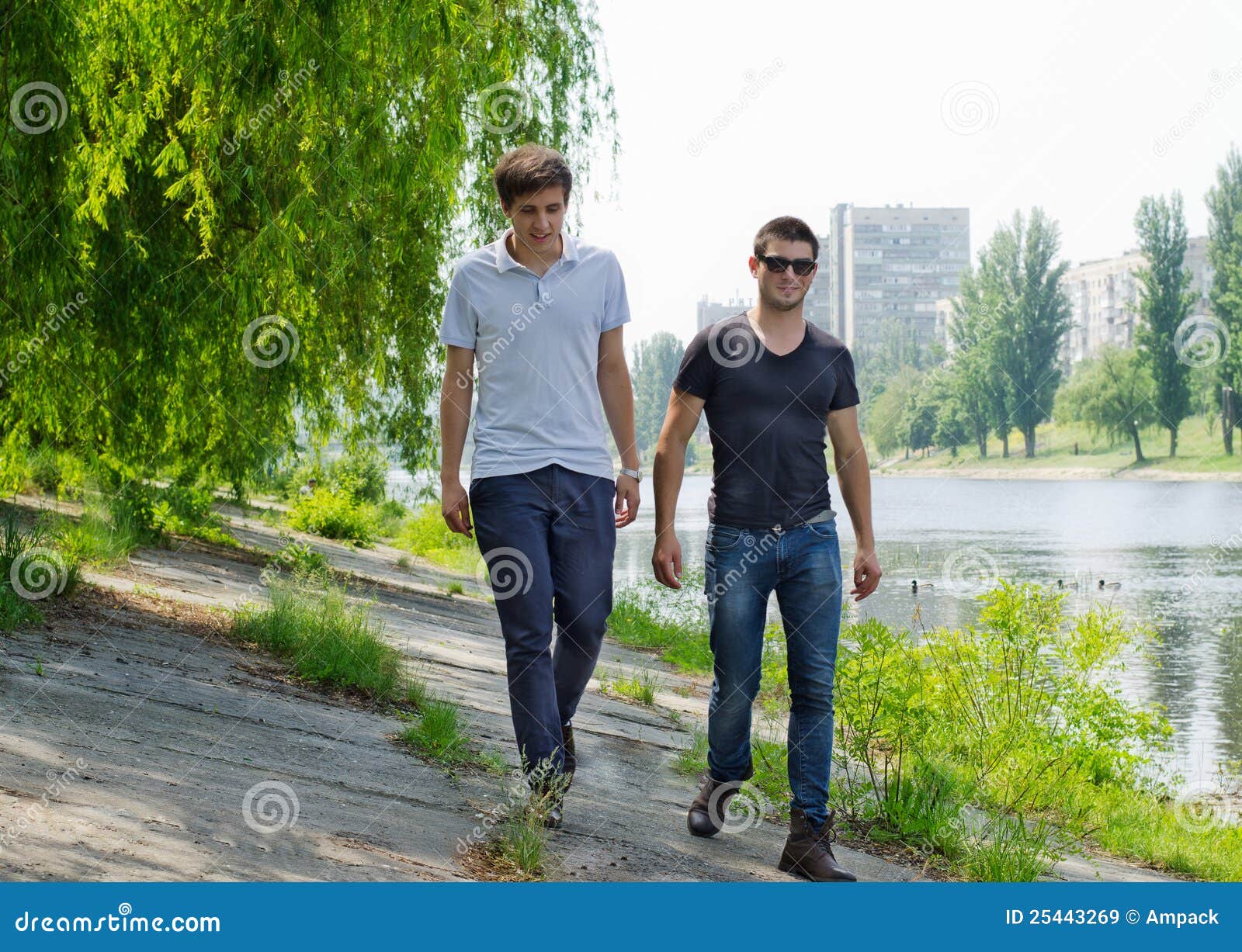 Two Young Men Walking Along a Riverbank Stock Image - Image of modern ...