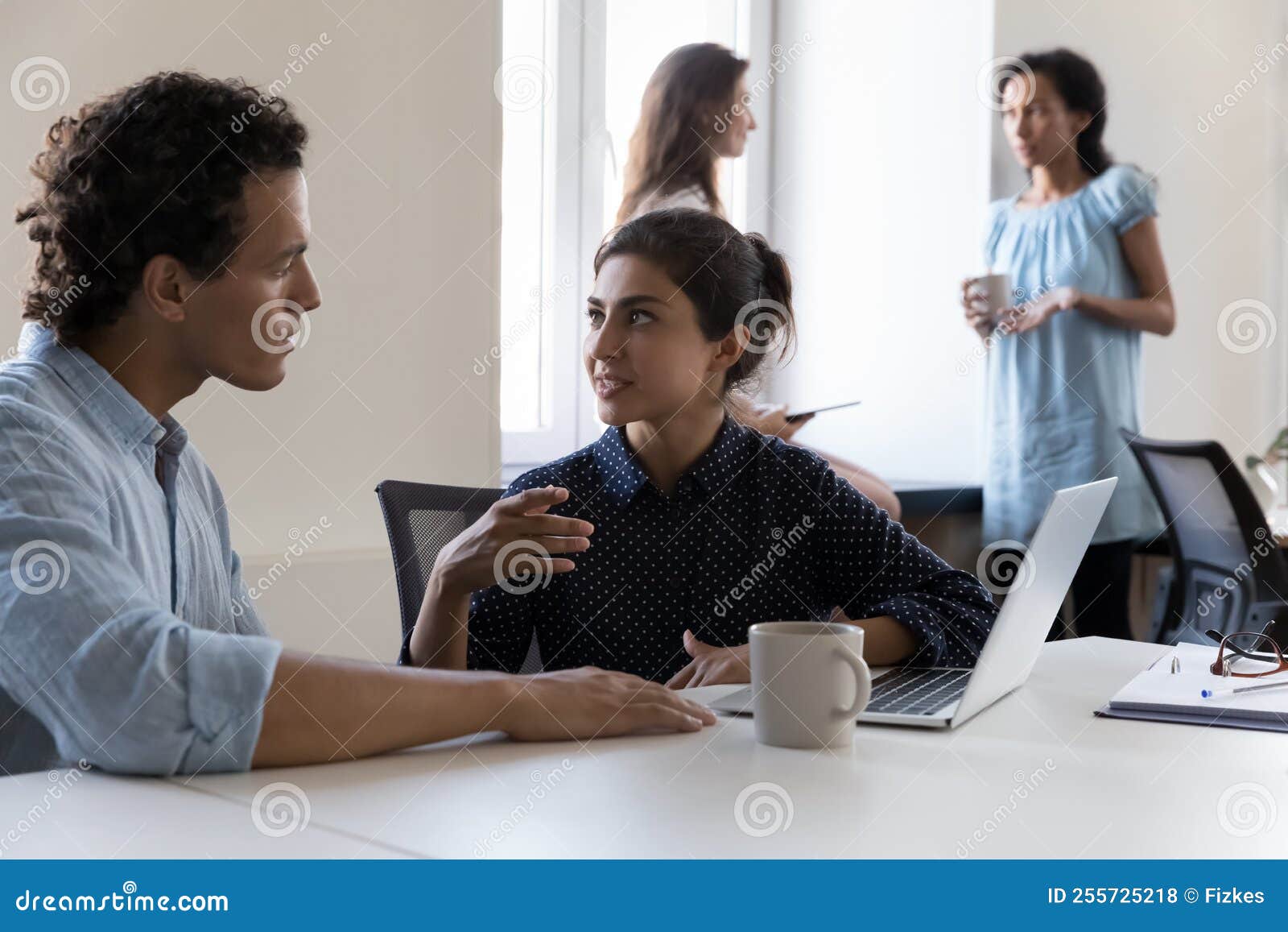 Two Young Multiethnic Employees Talking at Workplace, Discussing ...