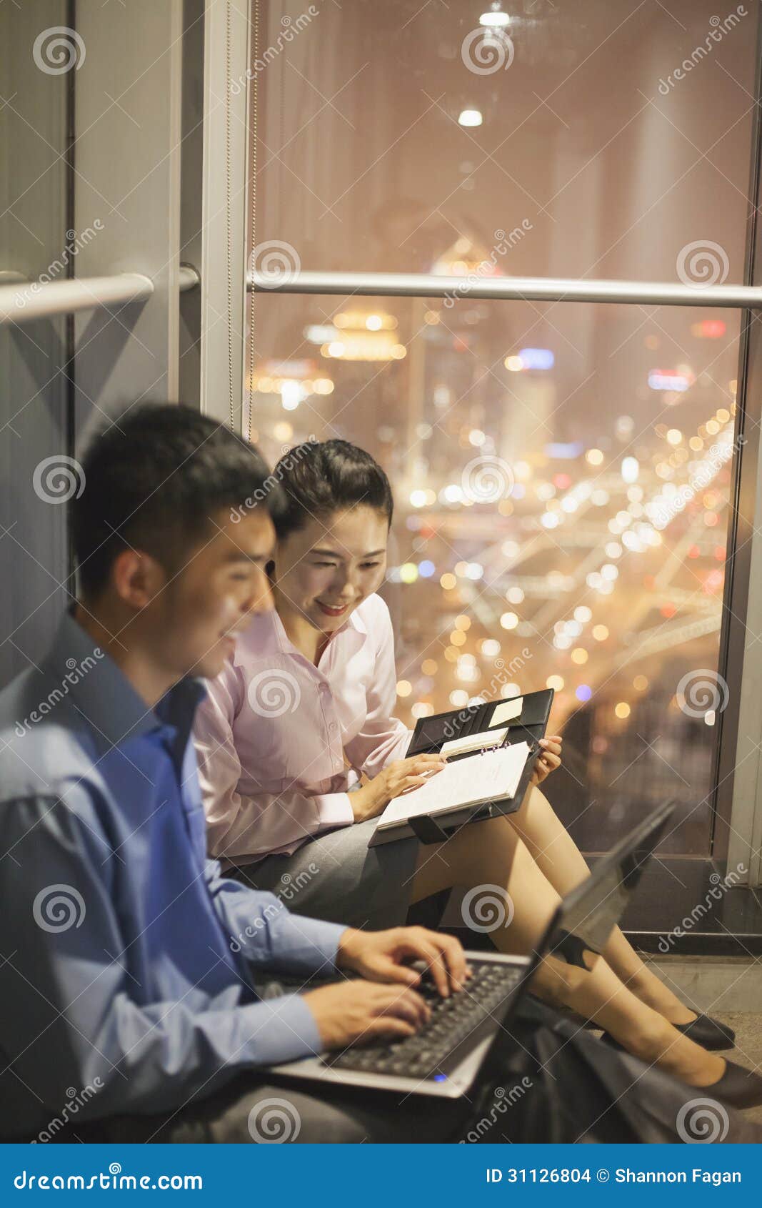 Two Young People Smiling and Working Together in the Office at Night ...