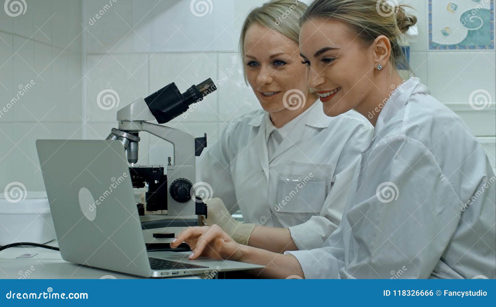 Two Young Positive Scientists Working in Laboratory Using Microscope ... Two Young Positive Scientists Working in Laboratory Using Microscope ...