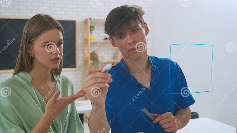 Two Young Students Draw Math Problems on the Glass with a Marker and ...