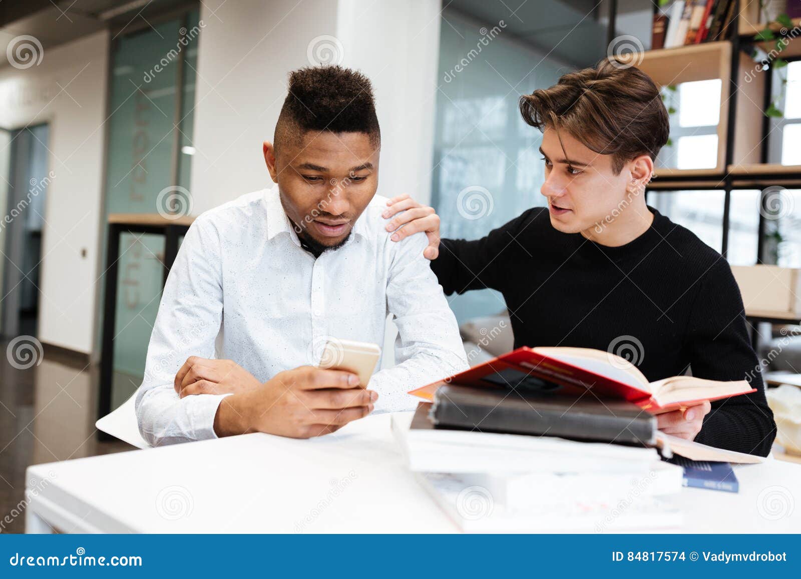Two Young Students in Library Choose between Book and Cellphone. Stock ...