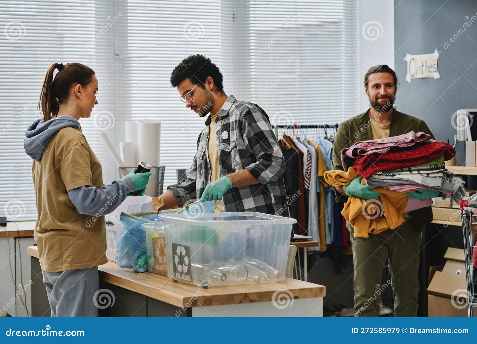 Two Young Volunteers Sorting Garbage while Man Carrying Stack of ...