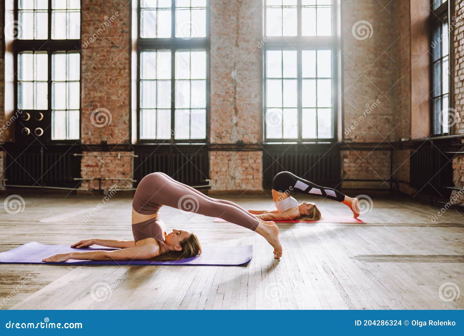Two Young Women Do Complex of Stretching Yoga Asanas in Loft Style ...