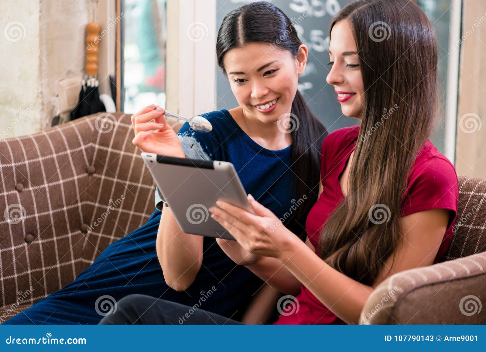 Two Young Women Laughing while Using a Tablet Stock Image - Image of ... Two Young Women Laughing while Using a Tablet Stock Image - Image of ...