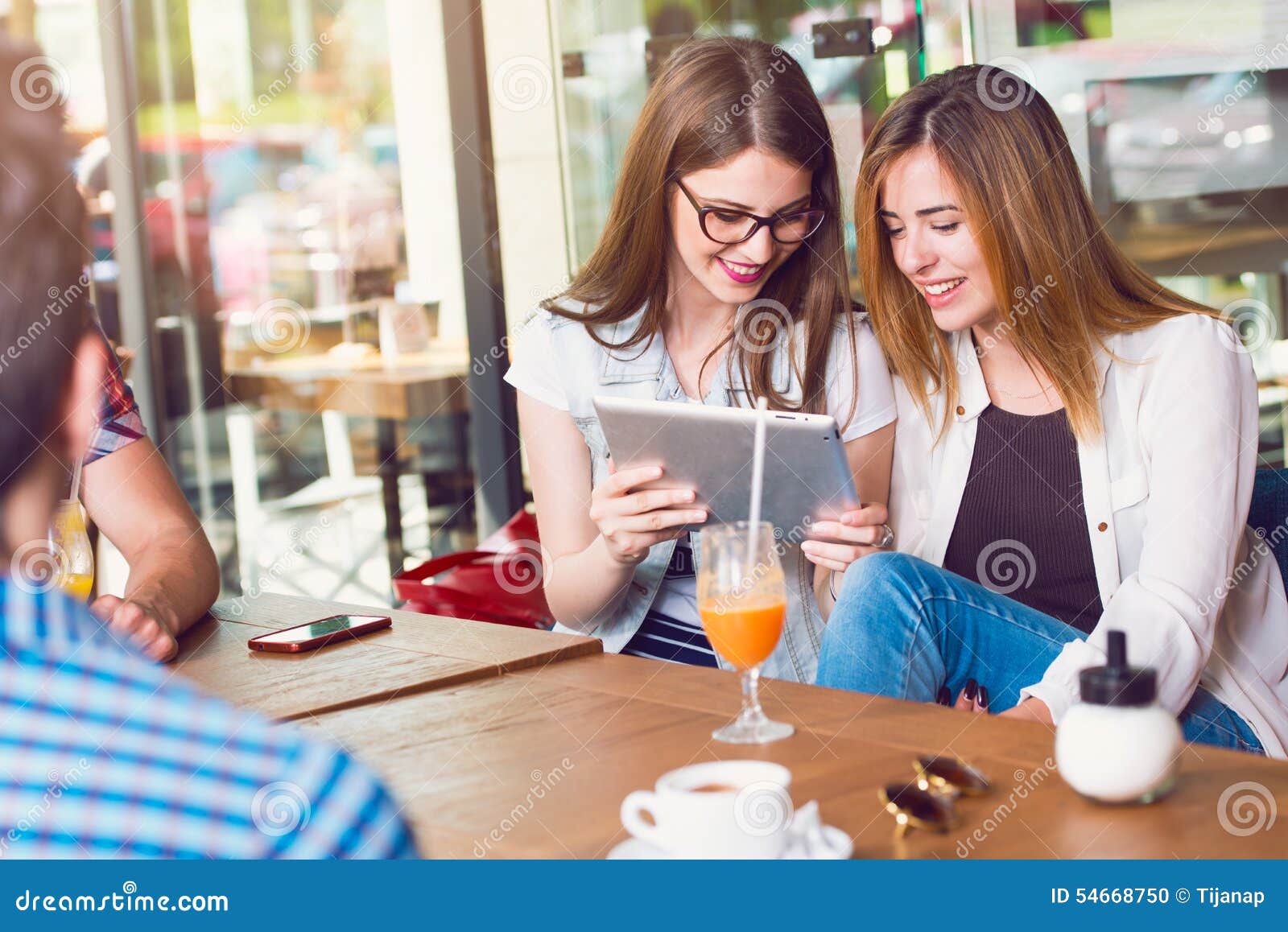 Two Young Women Looking at a Tablet Stock Photo - Image of person ...
