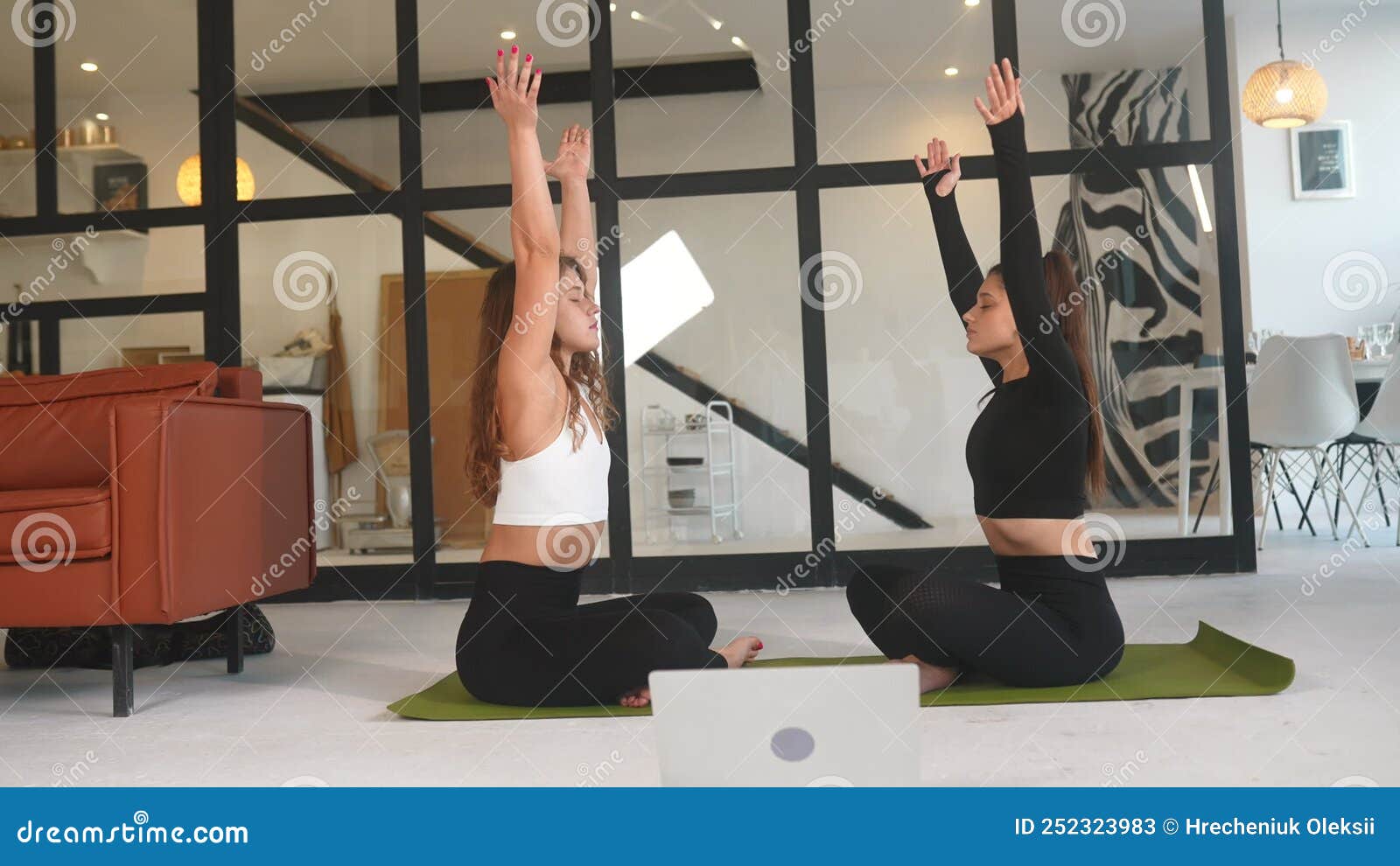 Two Young Women Meditating In Lotus Pose With Hands In Namaste Stock