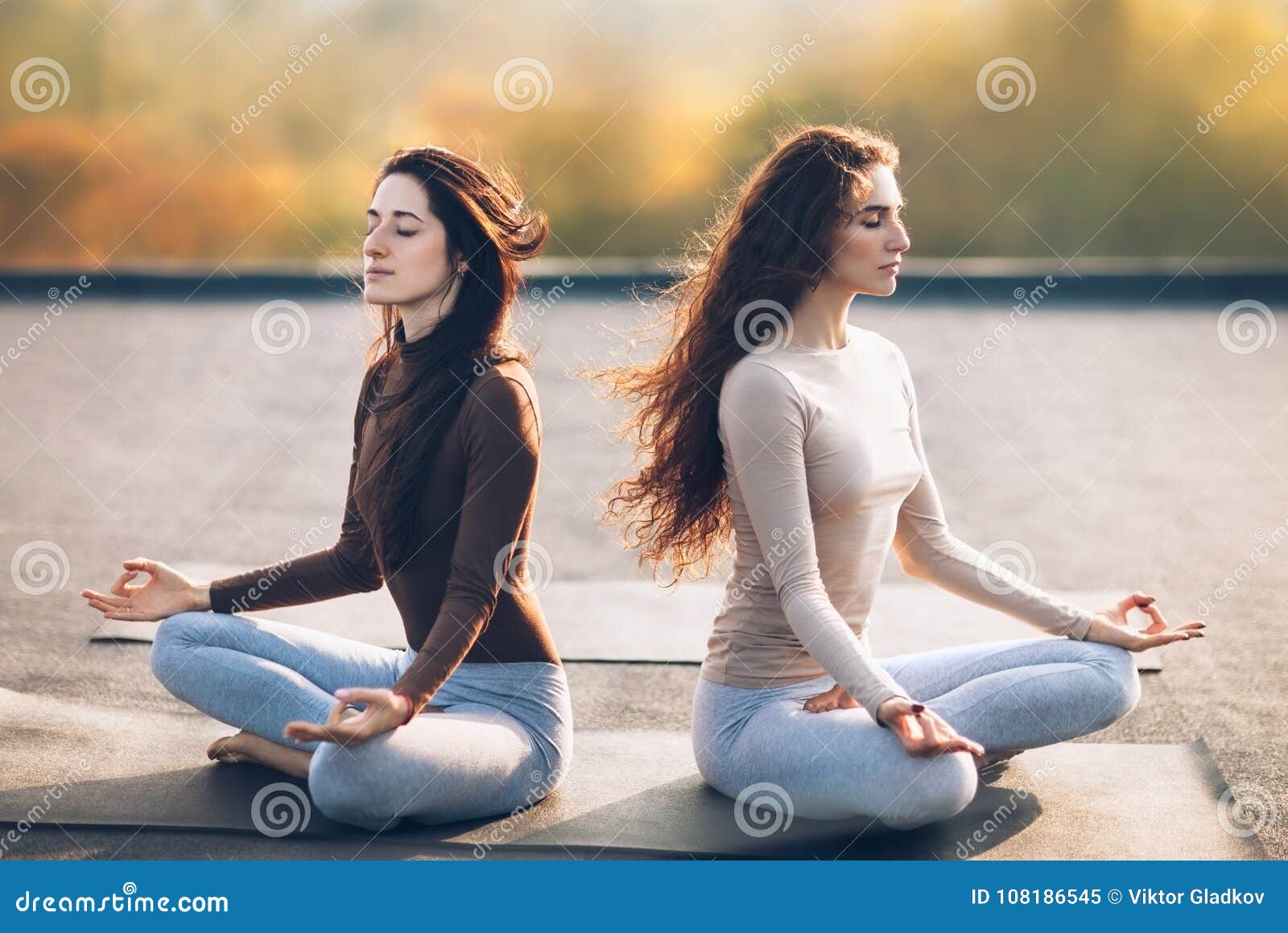 Two Young Women Meditating In Lotus Pose On The Roof Outdoor Stock