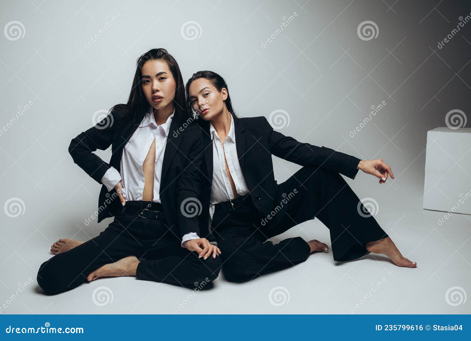 Two Young Women Pose in Studio Sitting Stock Photo - Image of elegant ...