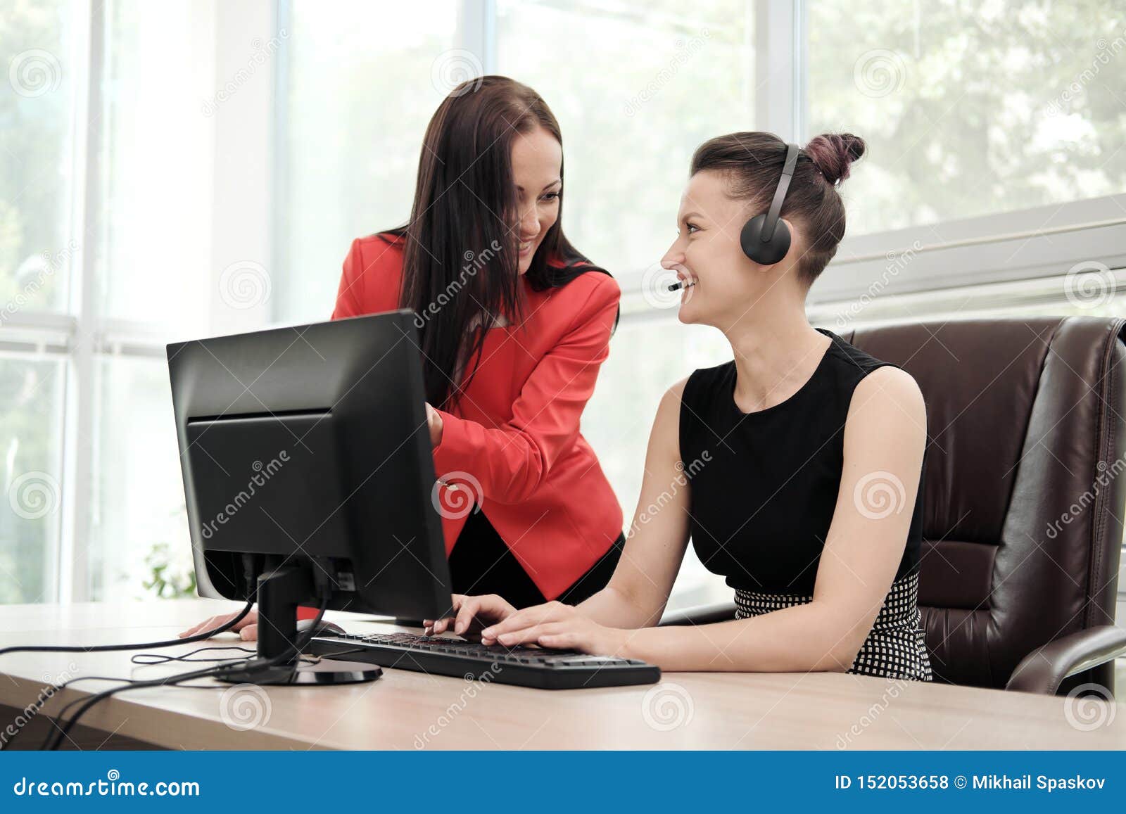 Two Young Women Work in a Bright Office at the Computer. Discuss ...
