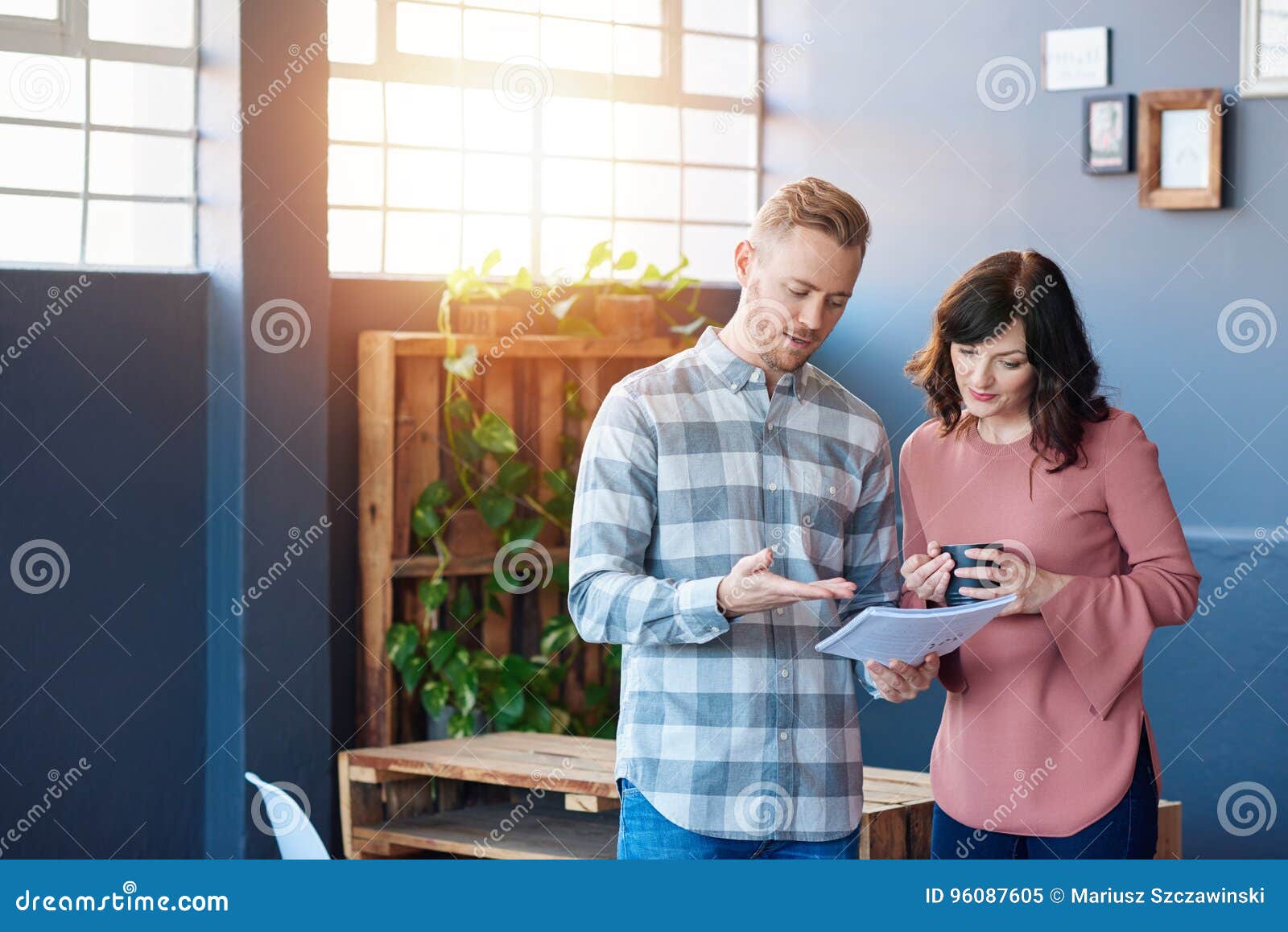 Two Young Work Colleagues Discussing Paperwork Together in an Office ...