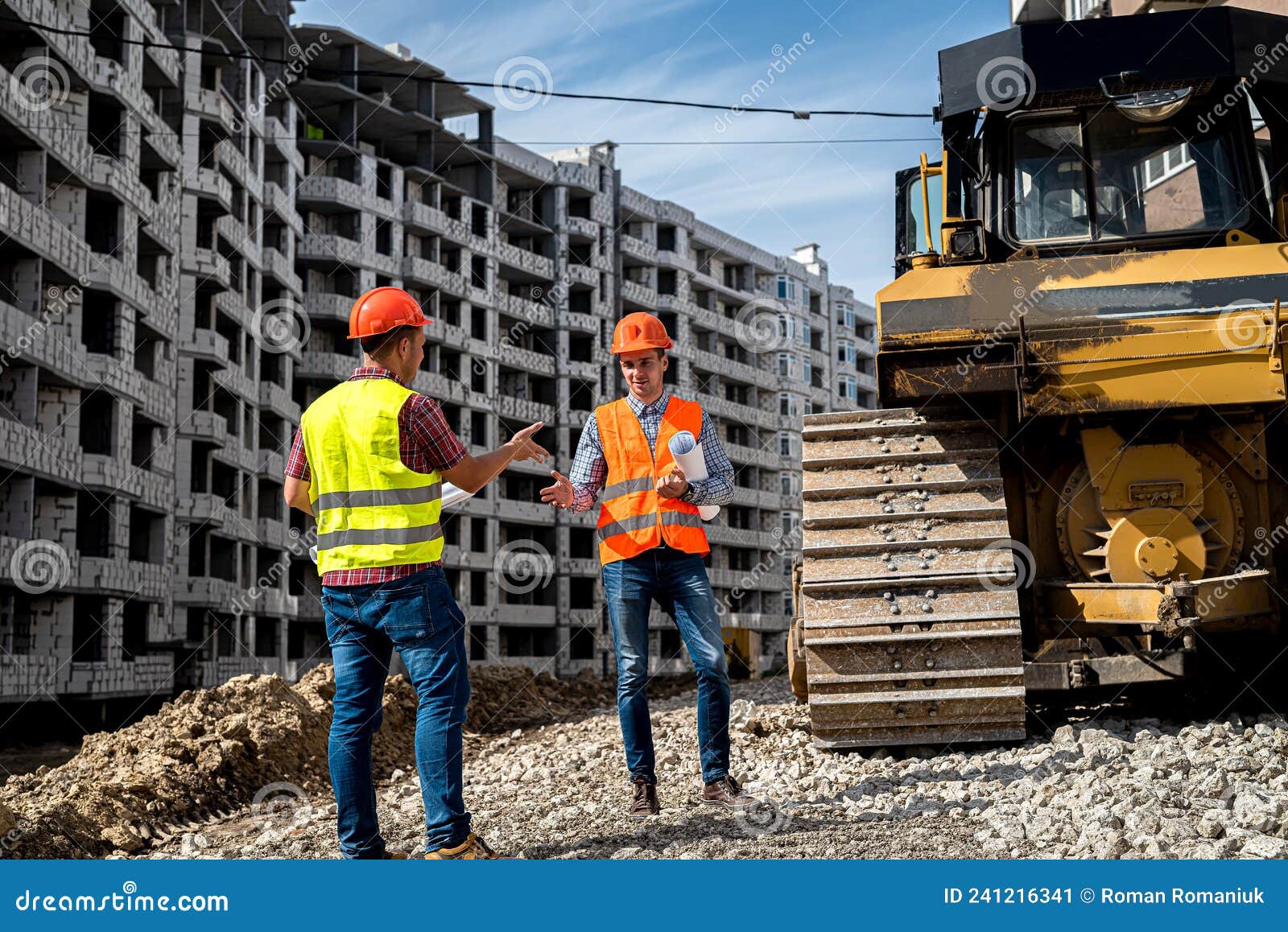 Two Young Workers in Overalls Stand with Their Backs Looking at the New ...