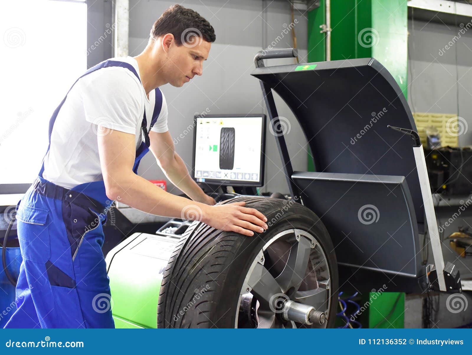 Tyre Change in a Garage - Assembler Balancing a Tyre on the Mach Stock ...
