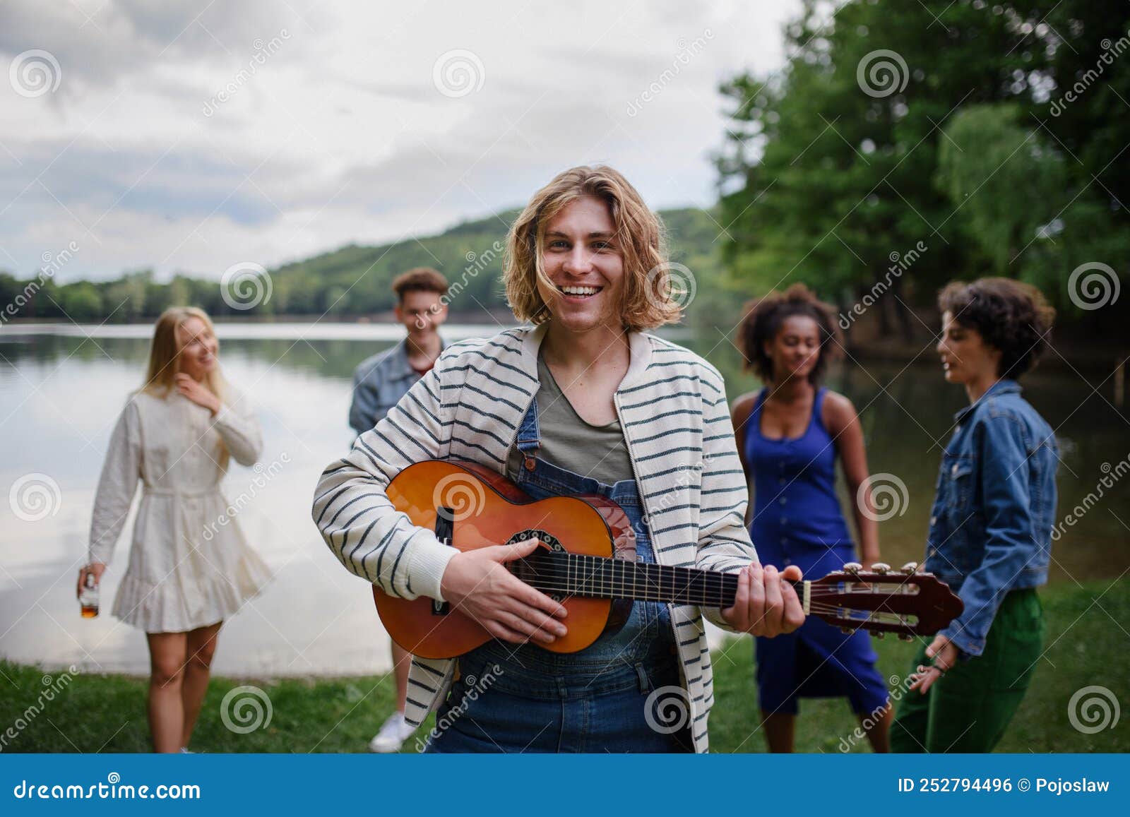 Um Grupo De Jovens Amigos Se Divertindo Perto De Um Lago Rindo E