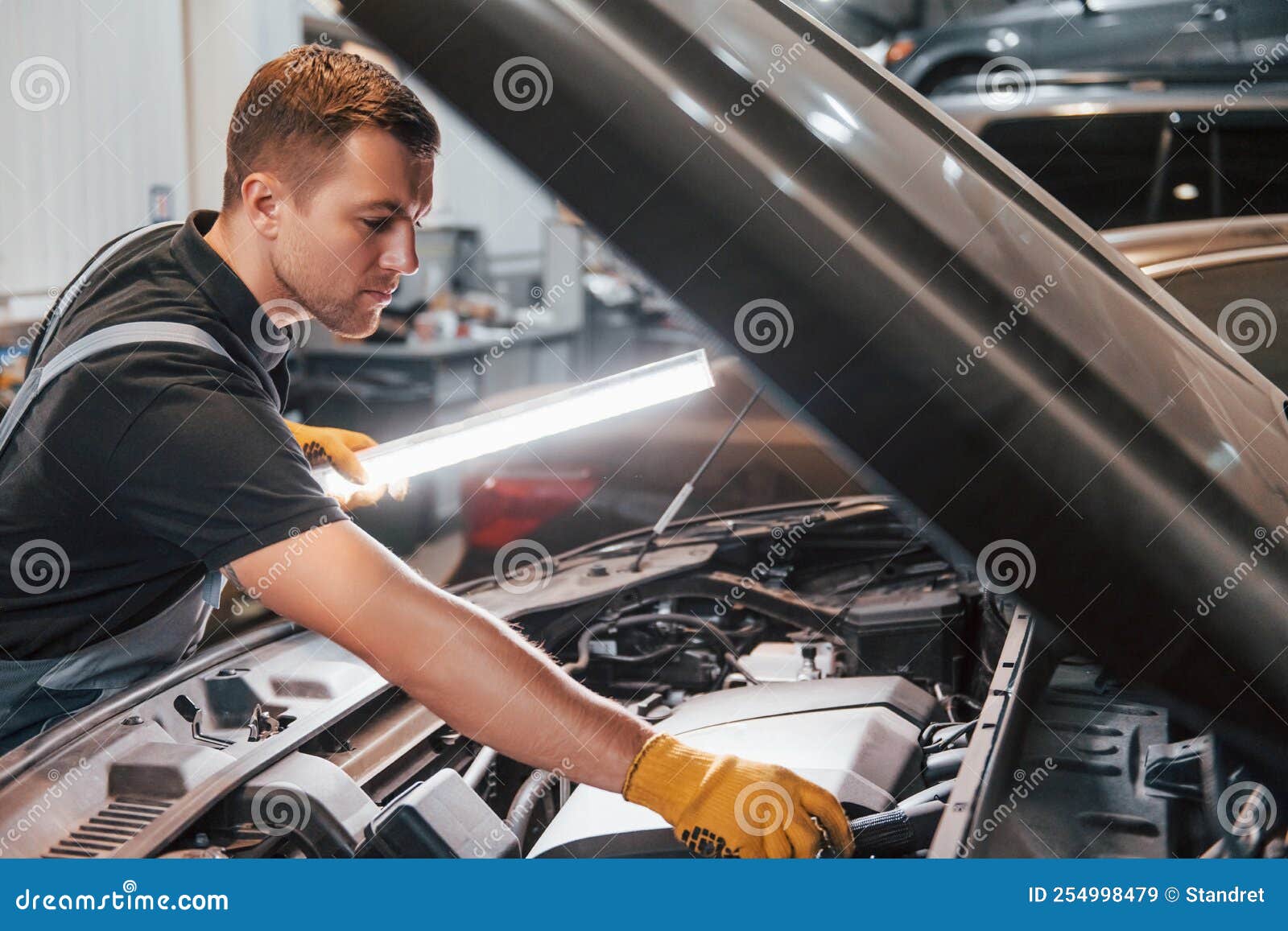 Under the Hood. Man in Uniform is Working in the Auto Service Stock ...