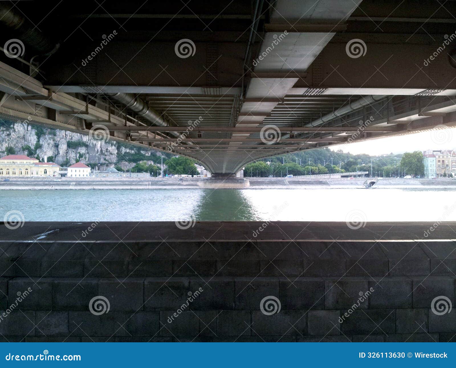 Underneath View of a Bridge Spanning a River with City Buildings in the ...