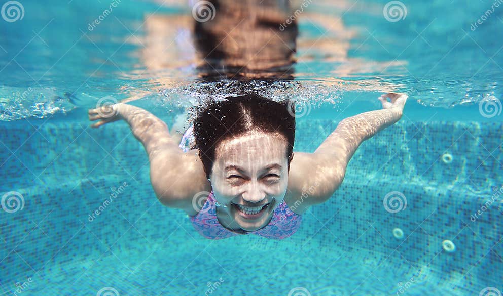 Underwater Shot Of Young Woman Diving Into The Swimming Pool Stock