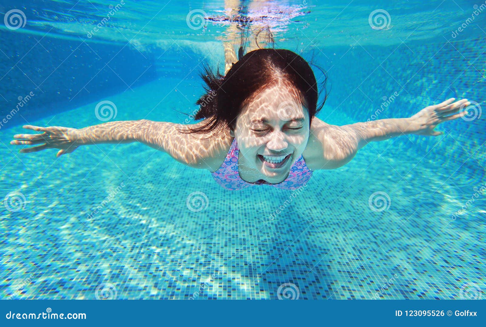 Underwater Shot Of Young Woman Diving Into The Swimming Pool Stock