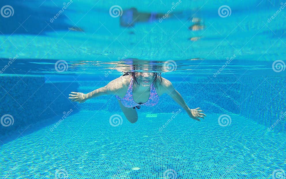 Underwater Shot Of Young Woman Diving Into The Swimming Pool Stock