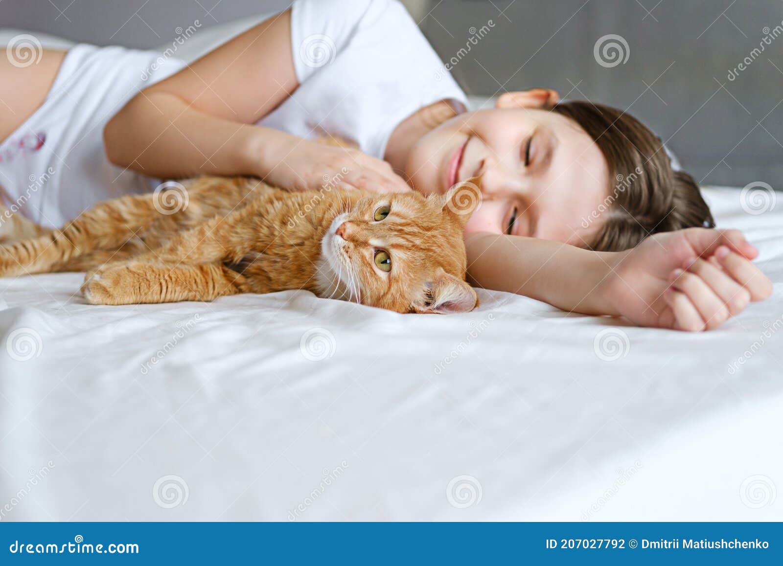 Une Fille Avec Un Chat Au Gingembre Se Trouve Sur Un Lit Blanc Une