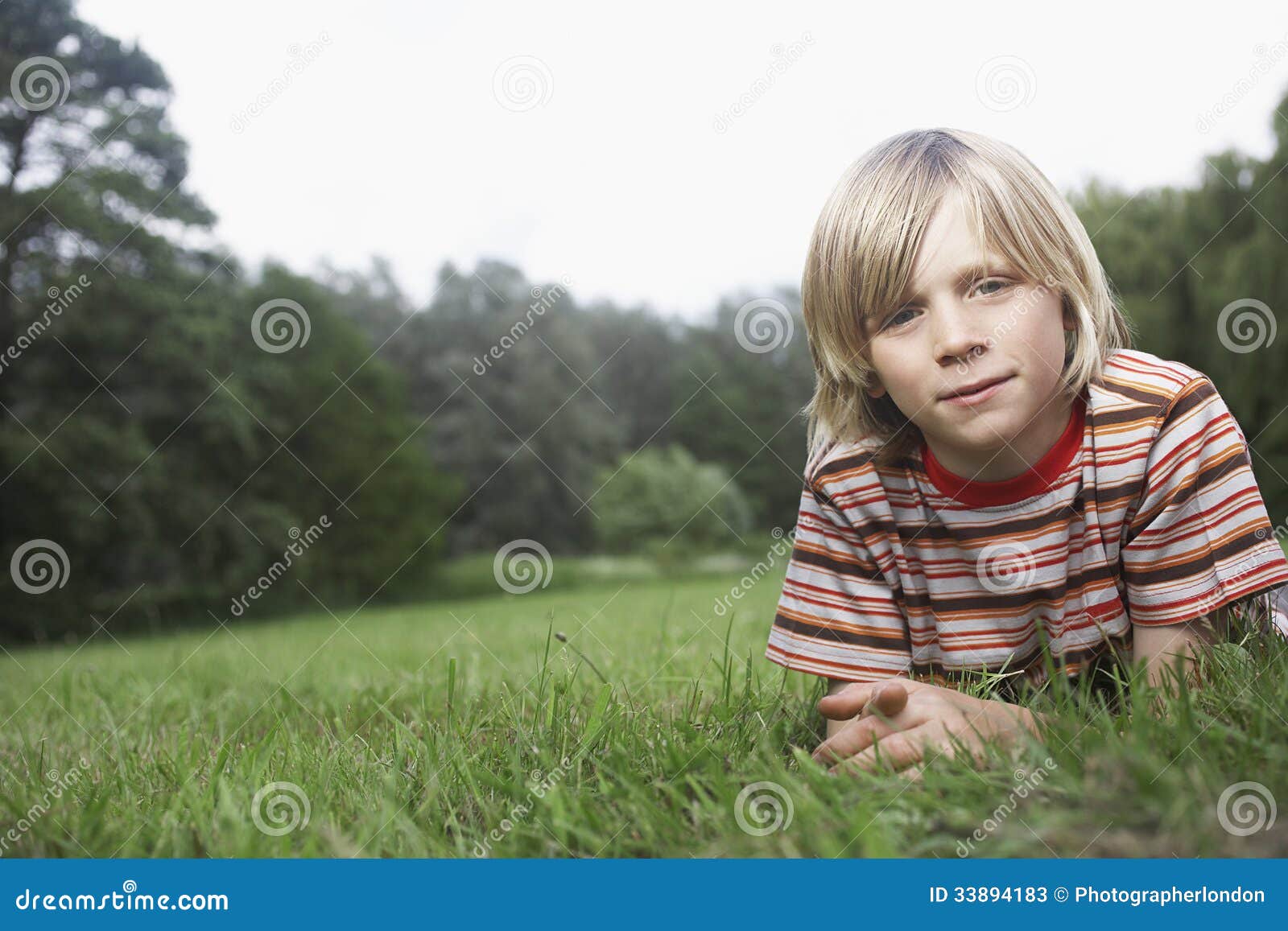 Ung pojke som ligger i äng fotografering för bildbyråer. Bild av ligga ...