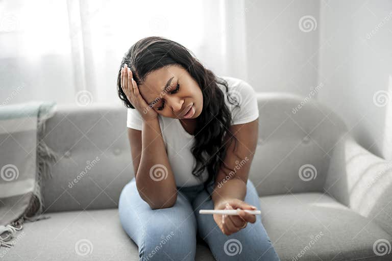 Unhappy Black Woman Looking At Pregnancy Test Upset By Result Sitting