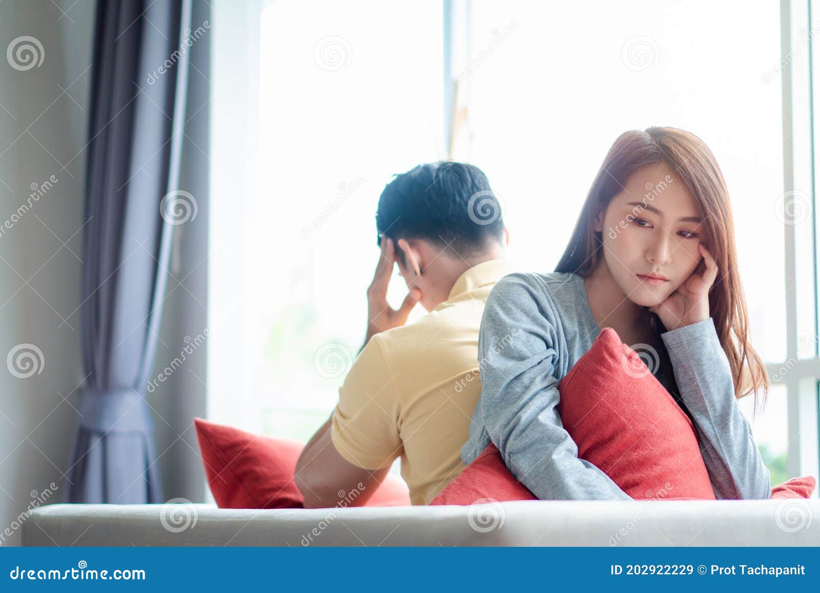 Unhappy Couple Sitting Behind Each Other On The Couch And Avoid Talking