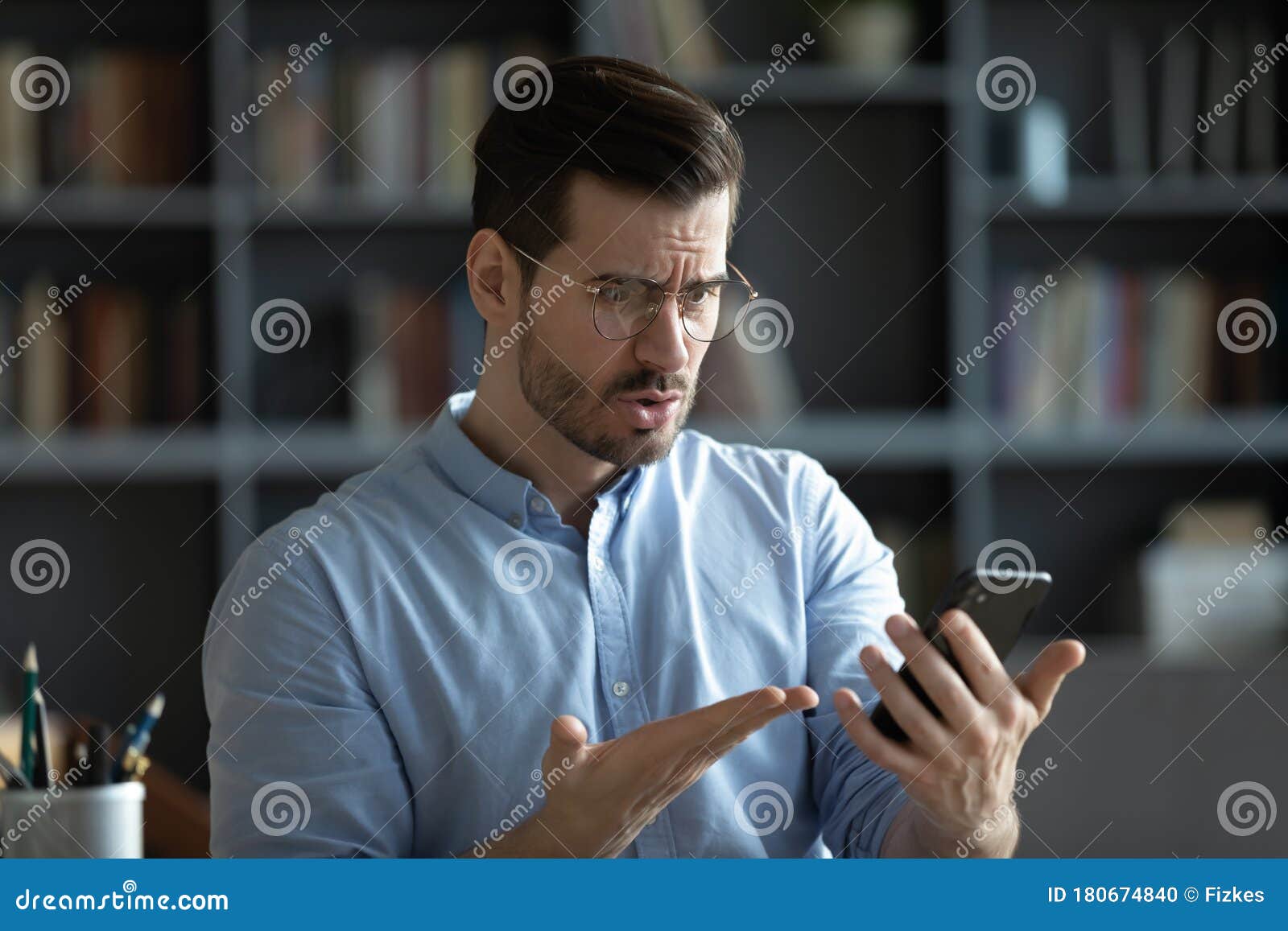 Unhappy Irritated Man Wearing Glasses Having Problem With Smartphone