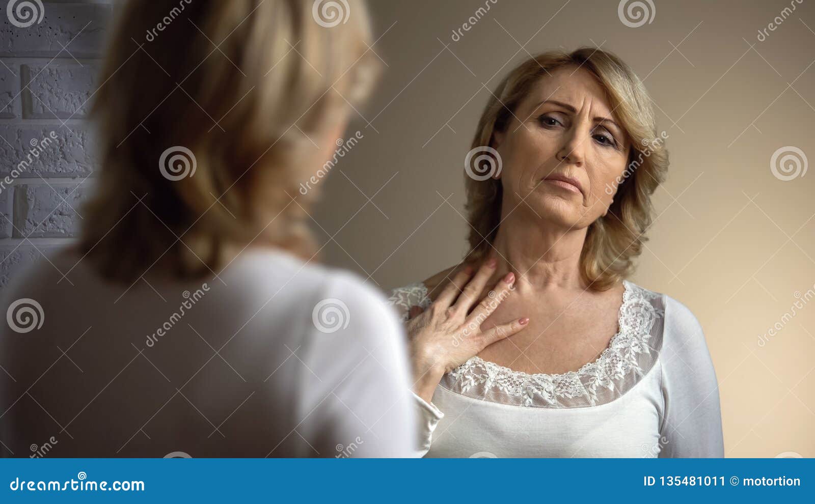 Unhappy Senior Woman Looking In Mirror And Touching Decollete Zone