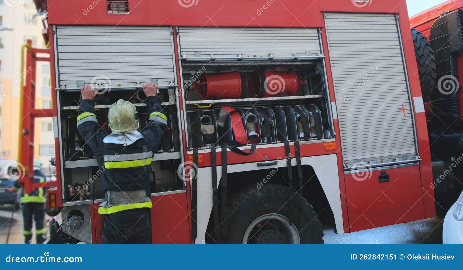 Uniformed Fireman Closes a Roller Shutter on the Side of a Fire Engine ...