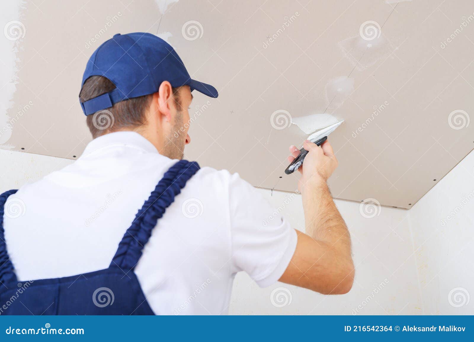A Uniformed Worker Puts Putty on the Caps of the Screws on the Ceiling ...